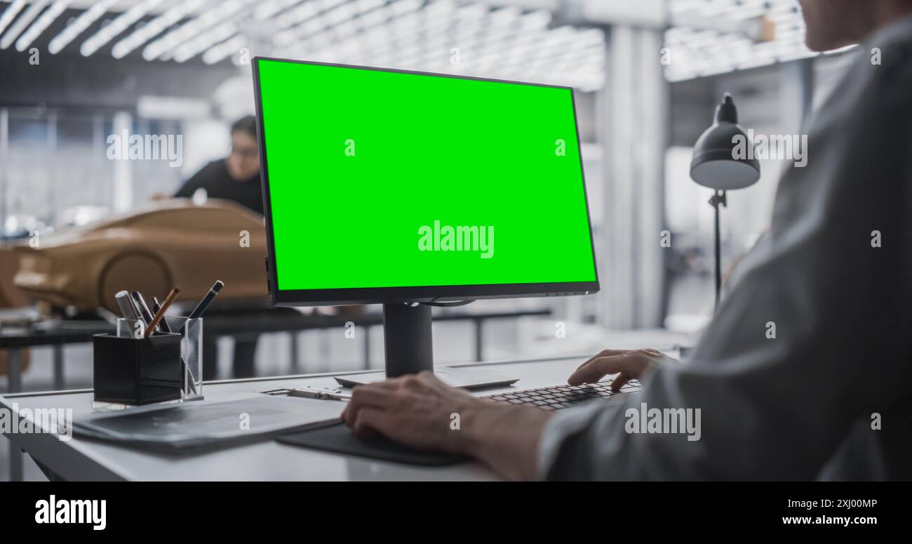 Automotive Designer Working on a Desktop Computer with Green Screen Mock Up Display. Digital ...