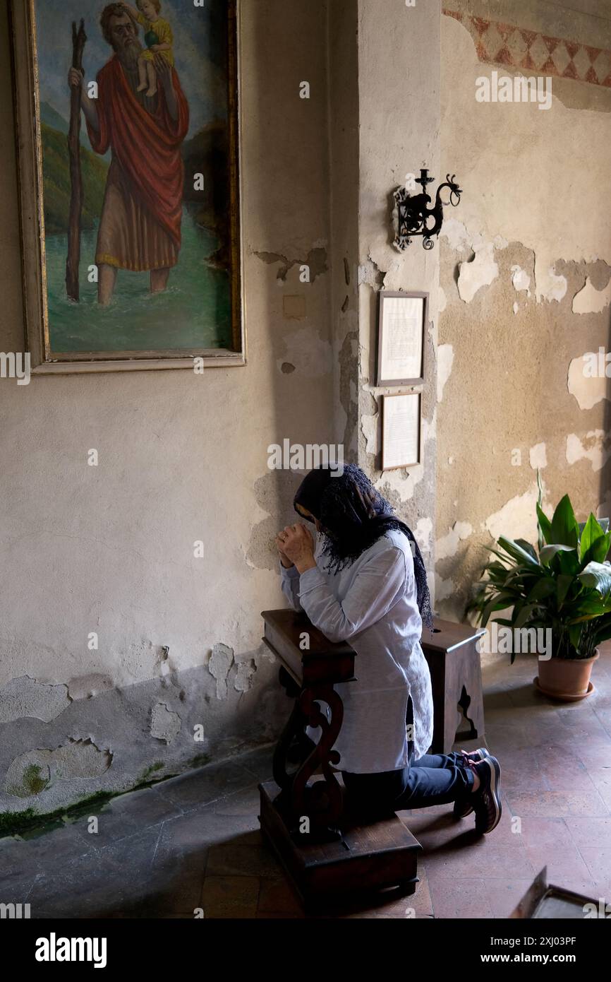 Christian woman praying in small street chapel in Volterra, Tuscany ...