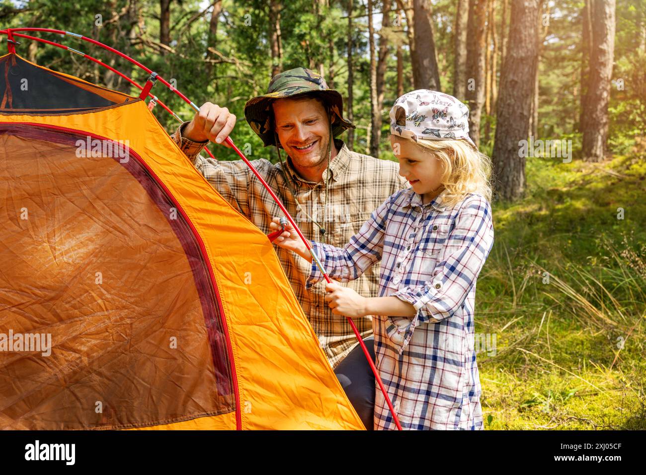 father with daughter setting up camping tent in forest. family outdoor ...