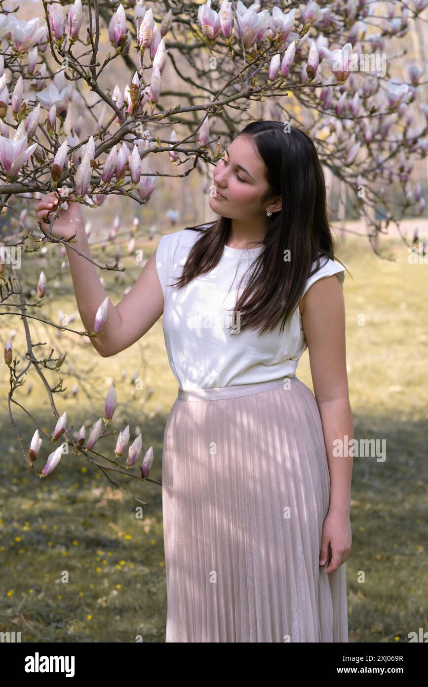 Spring portrait of a young, dark-haired girl in blooming magnolia ...