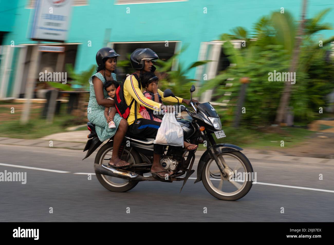 A family riding on a motorcycle in Hikkaduwa, Sri Lanka. An adult ...