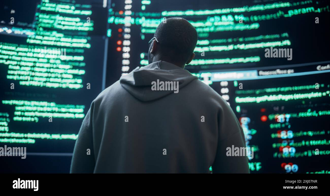 Back View of Young Black Man Looking at Big Digital Screens Glitching While Displaying Code ...