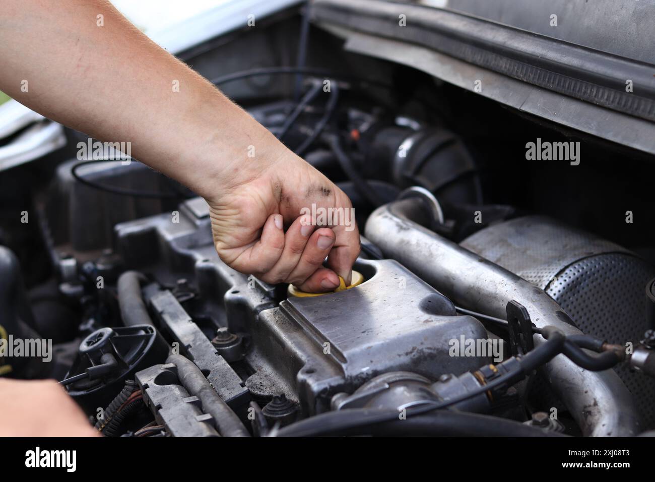 Change of oil. A man's hand opens or closes the oil filler cap ...