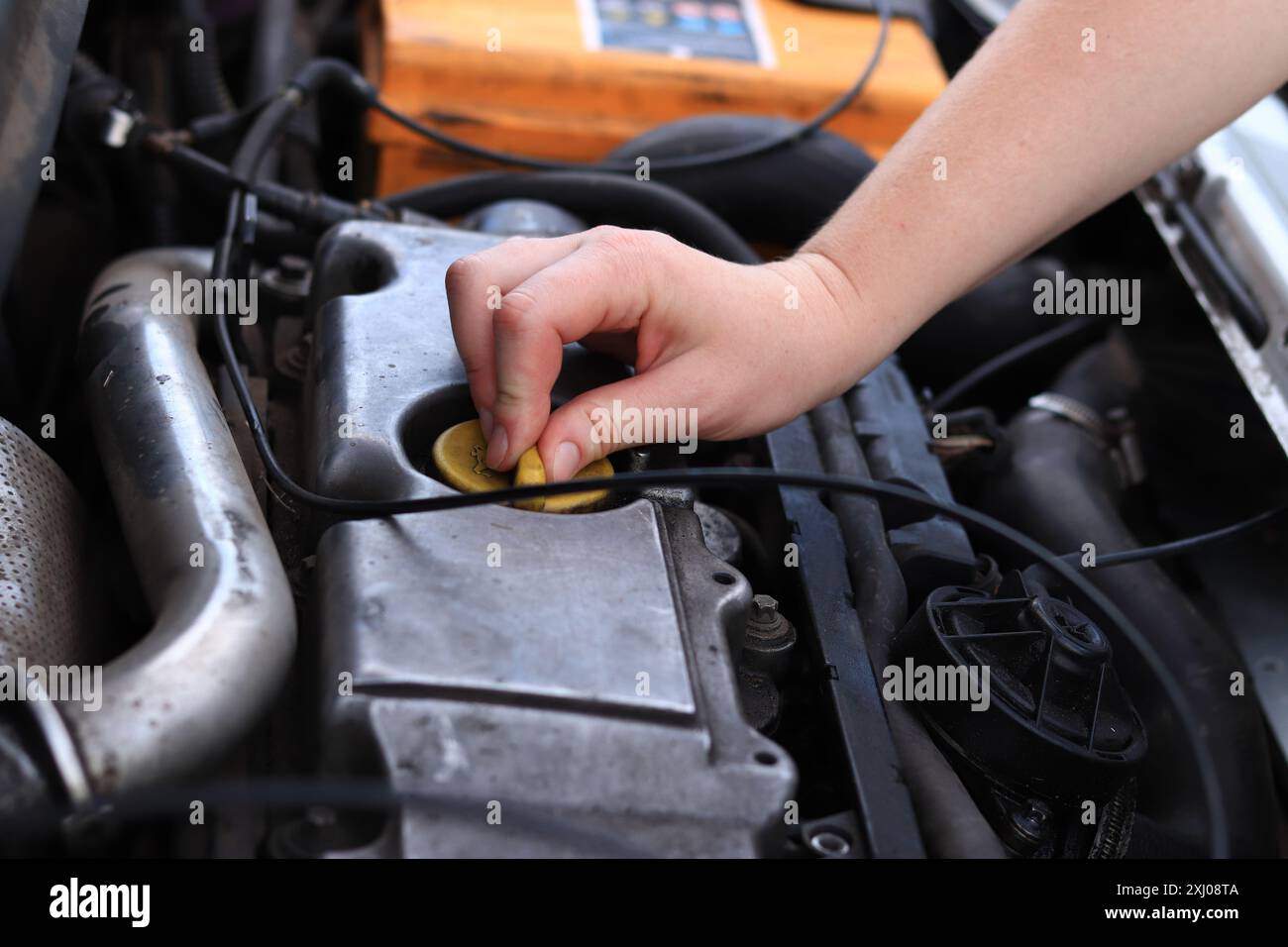 Change of oil. A woman's hand opens or closes the oil filler cap ...