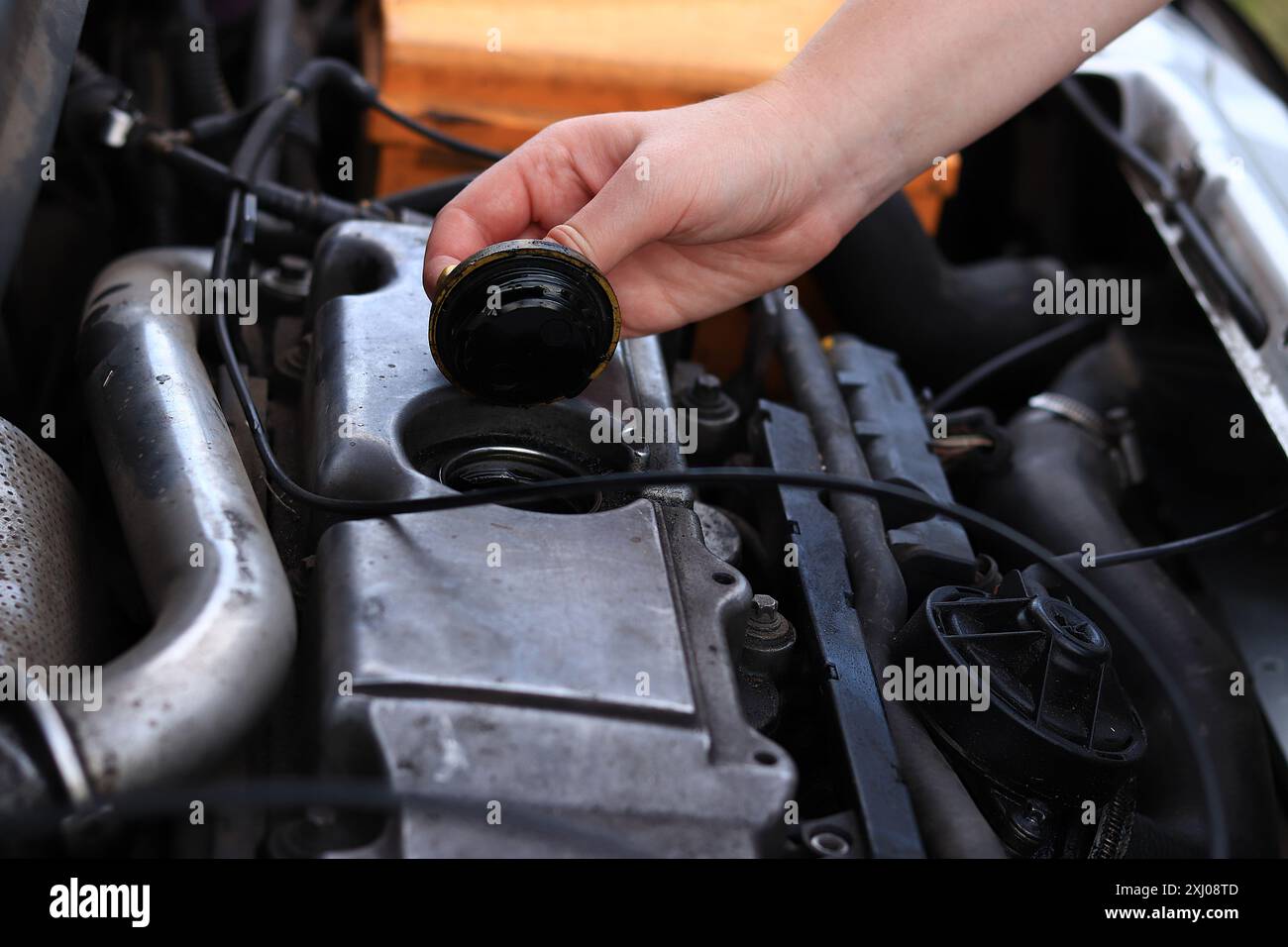Change of oil. A woman's hand opens or closes the oil filler cap ...