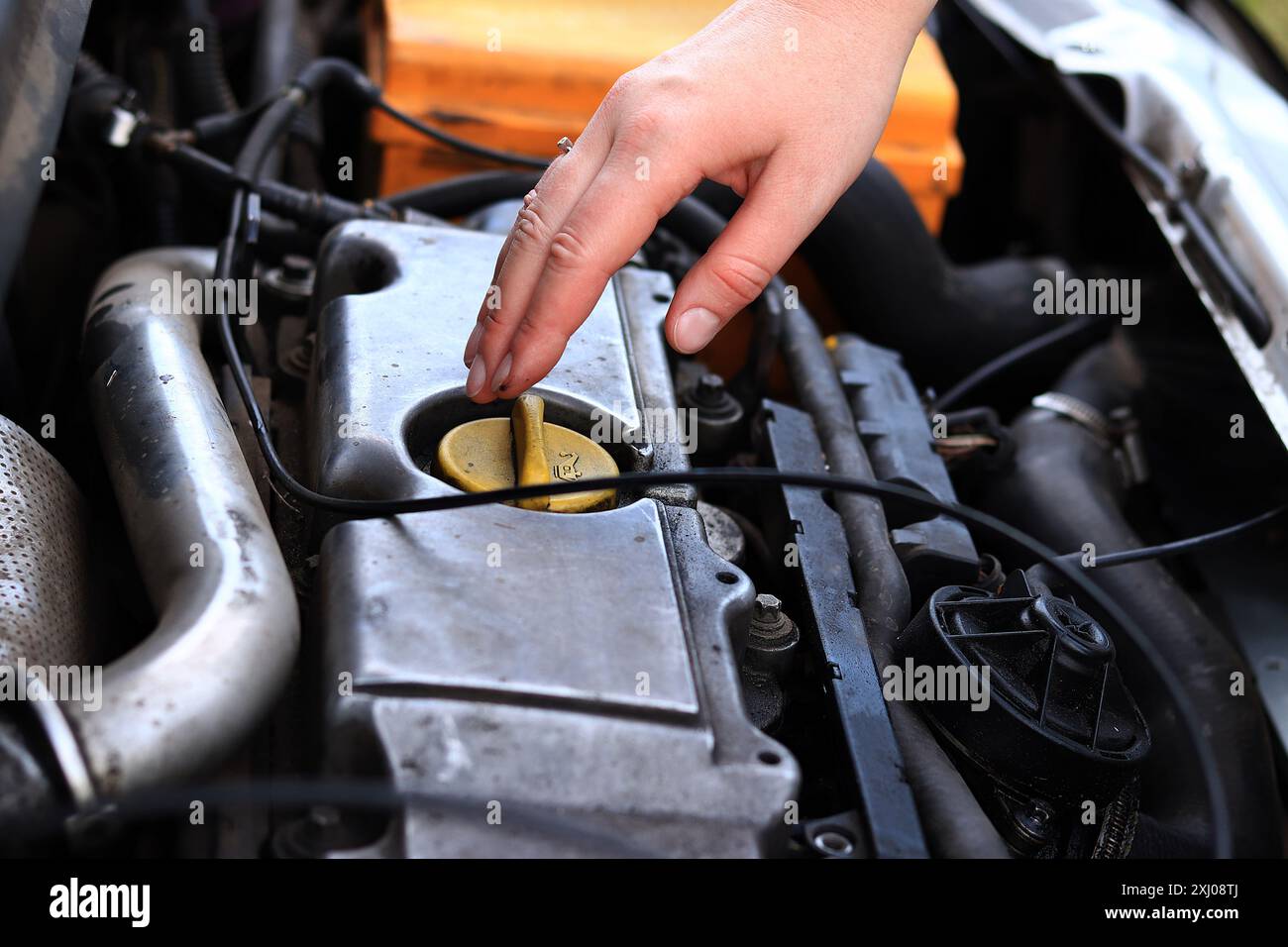 Change of oil. A woman's hand opens or closes the oil filler cap ...