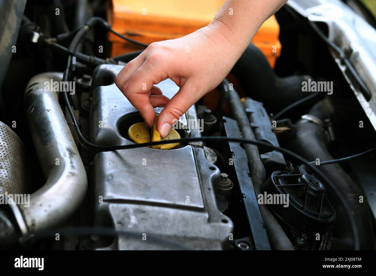 Change of oil. A woman's hand opens or closes the oil filler cap ...