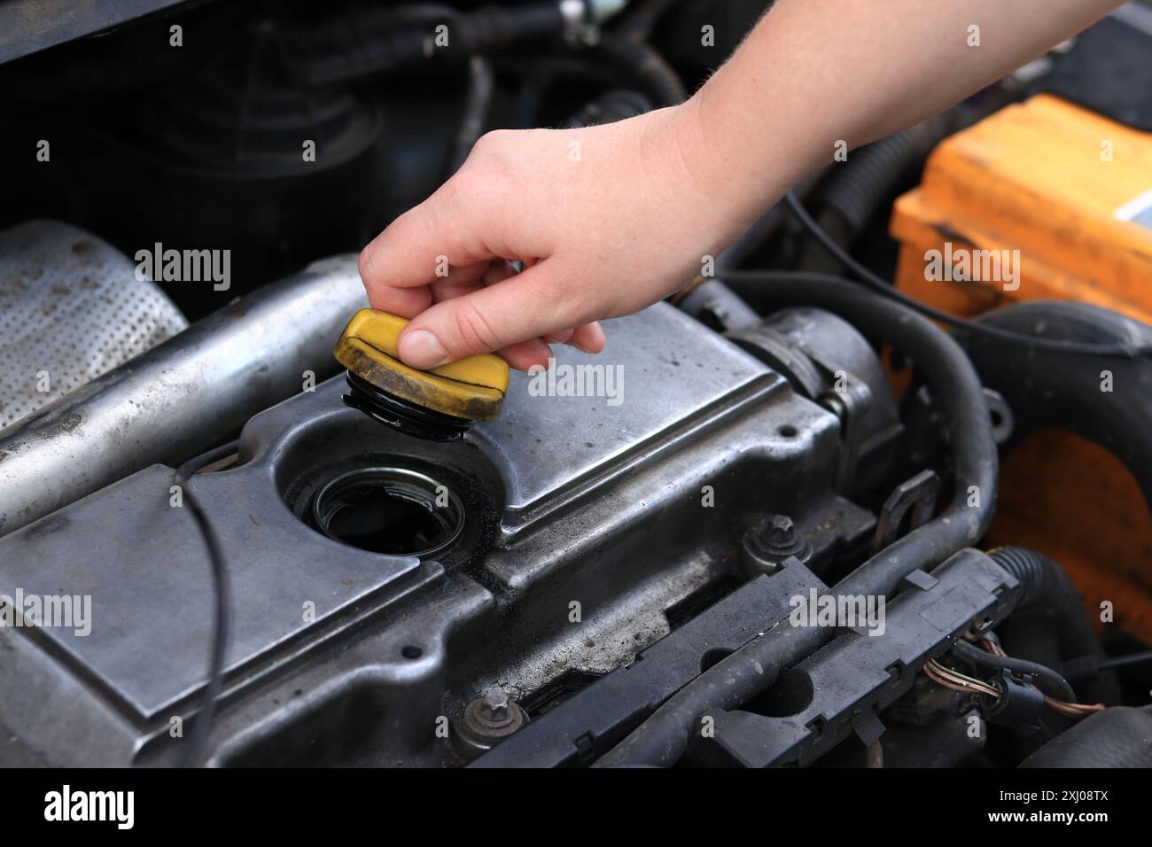 Change of oil. A woman's hand opens or closes the oil filler cap ...