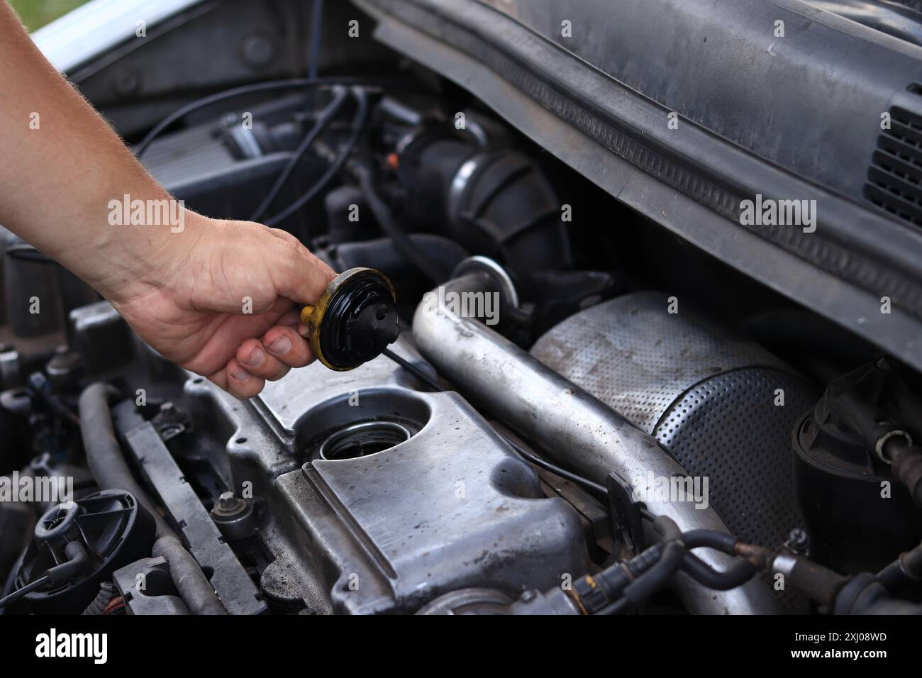 Change of oil. A man's hand opens or closes the oil filler cap ...