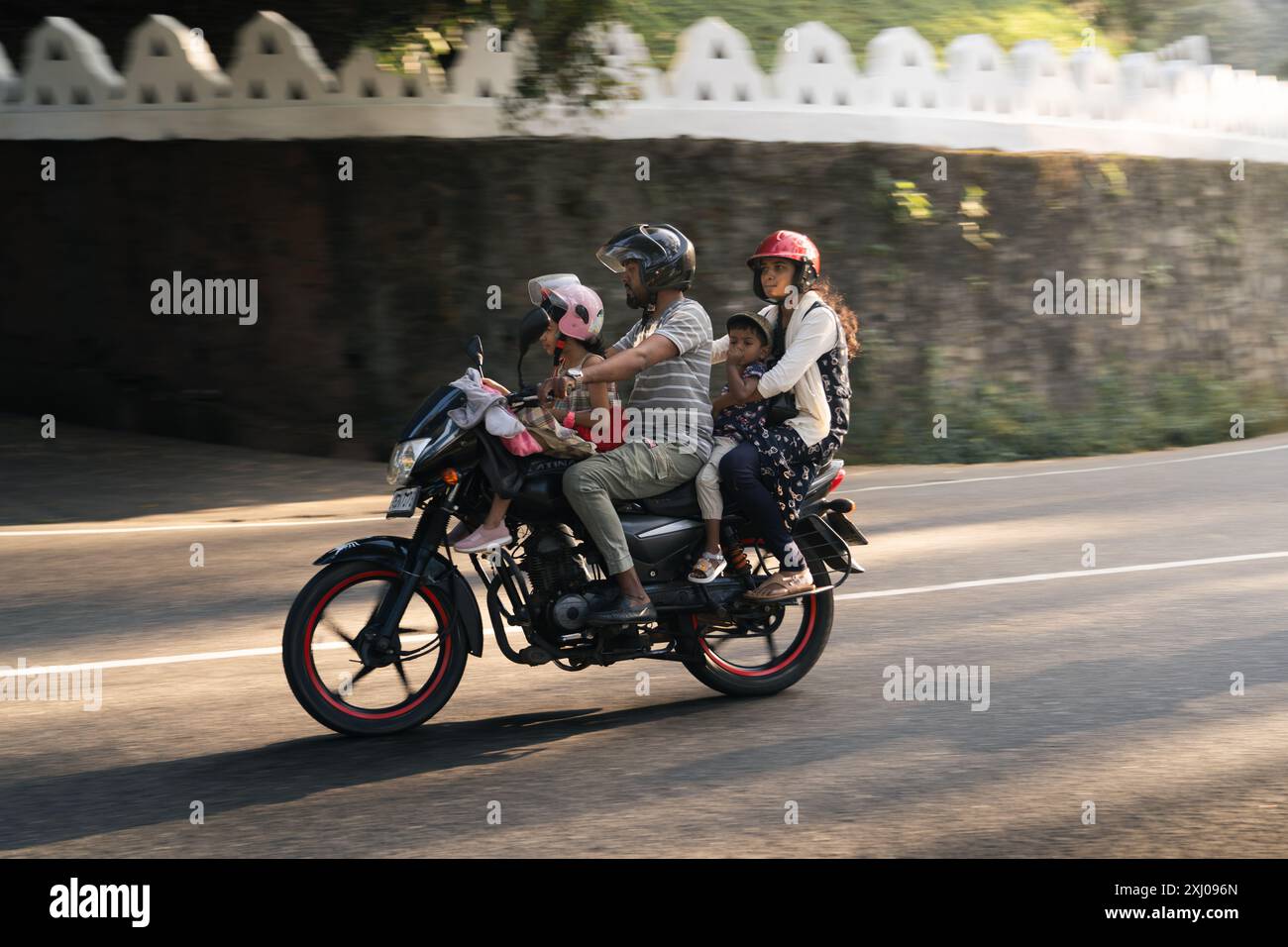 A family riding on a motorcycle in Kandy, Sri Lanka. An adult drives ...
