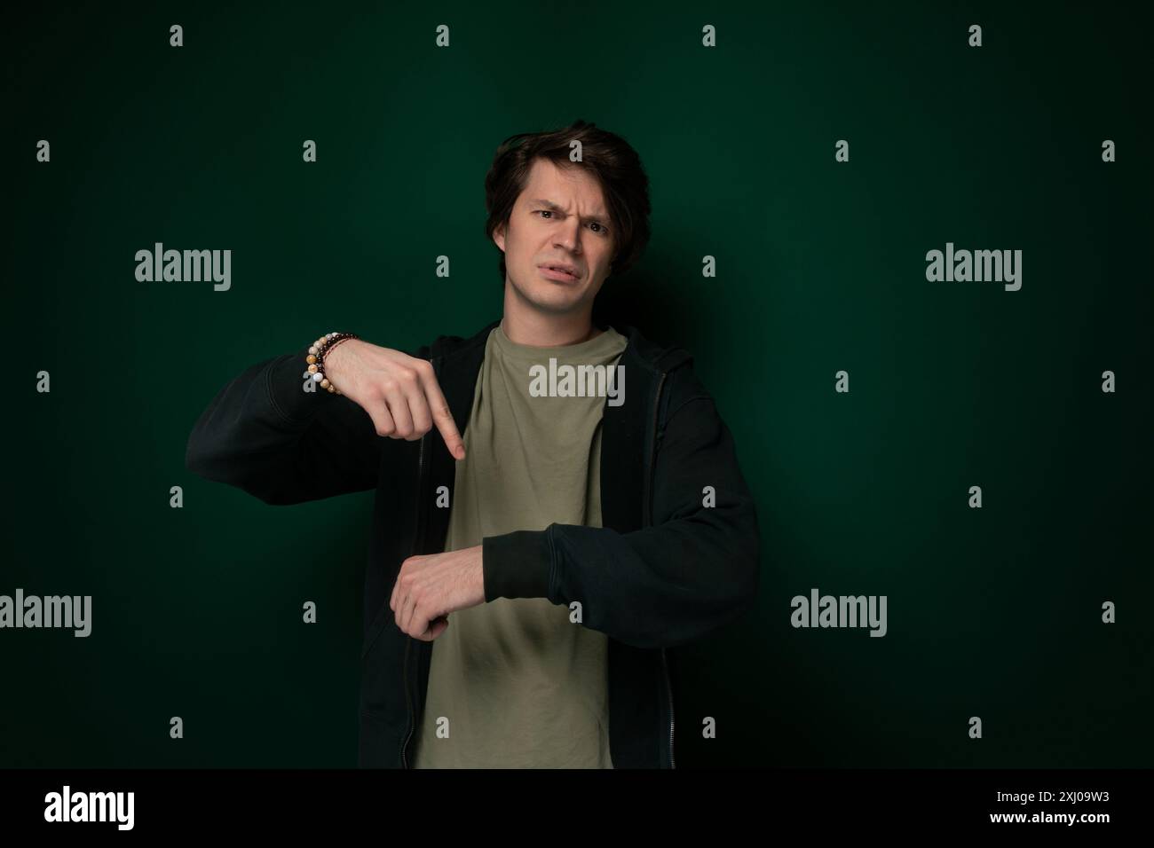 A man in a black jacket is pointing directly at the camera, making eye ...