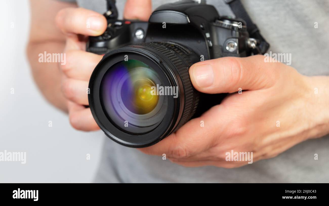 A close-up of a persons hand adjusting a camera lens while holding a ...