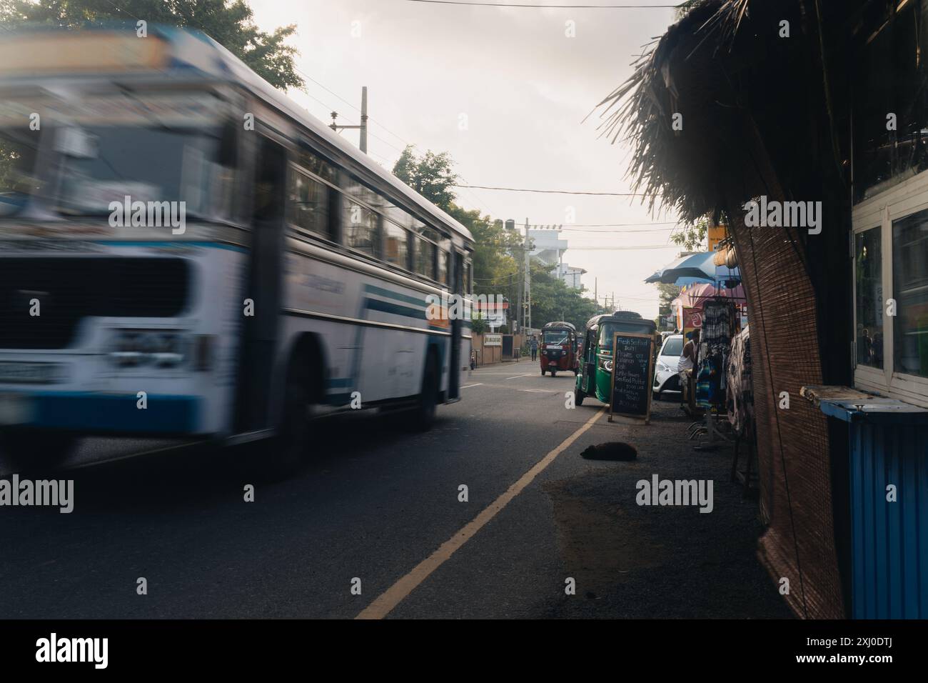 A daylight street scene in Mirissa, Sri Lanka, with an old bus driving ...