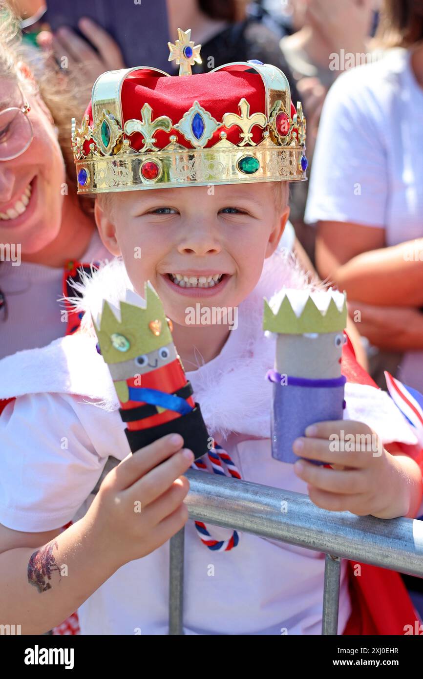 A young well-wisher carrying homemade models of the King and Queen wait ...