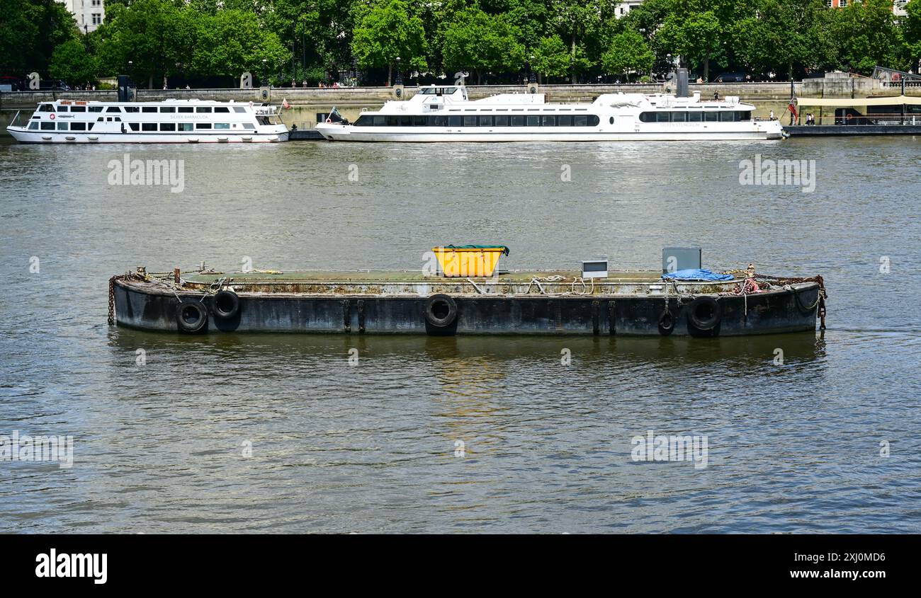 Yellow skip on barge anchored in River Thames, London, England, UK ...