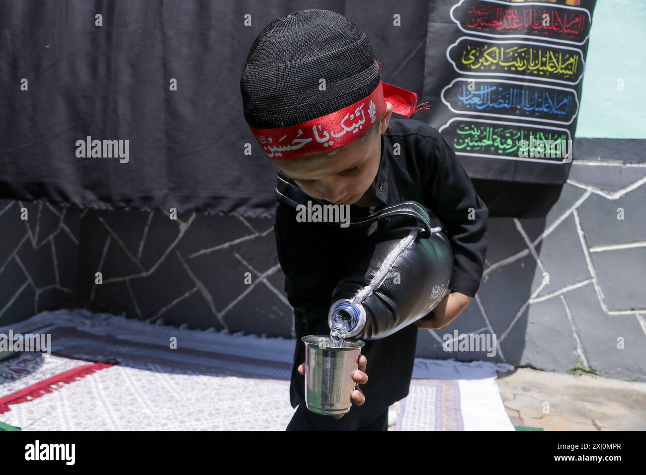 Srinagar, Jammu And Kashmir, India. 16th July, 2024. A Kashmiri Shia boy serves water to ...