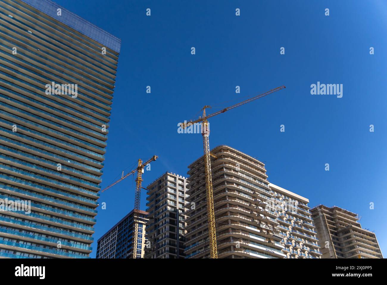 Yellow cranes on the background of multi-storey buildings under ...