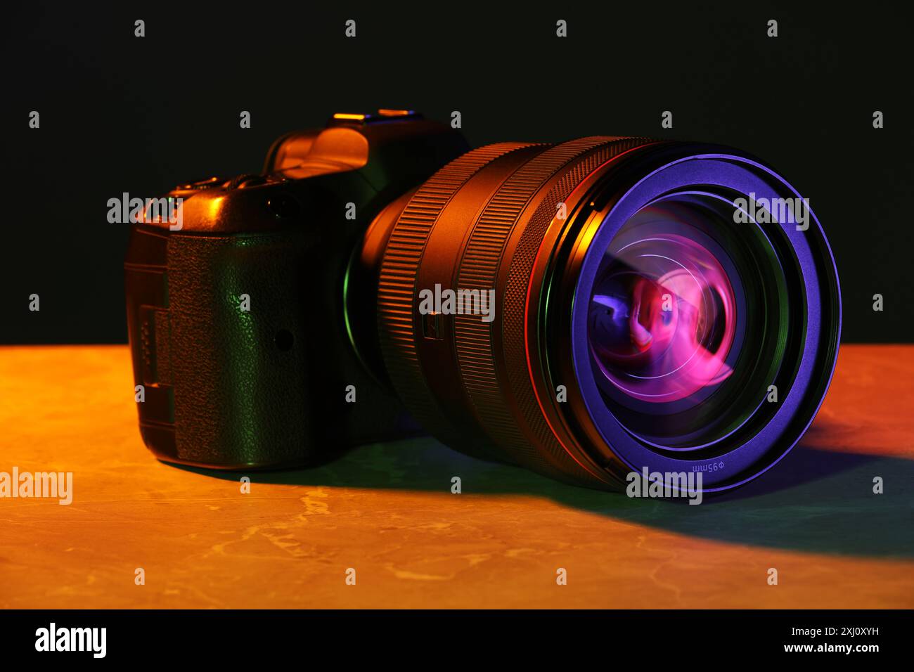 Modern photo camera in neon lights on table Stock Photo - Alamy
