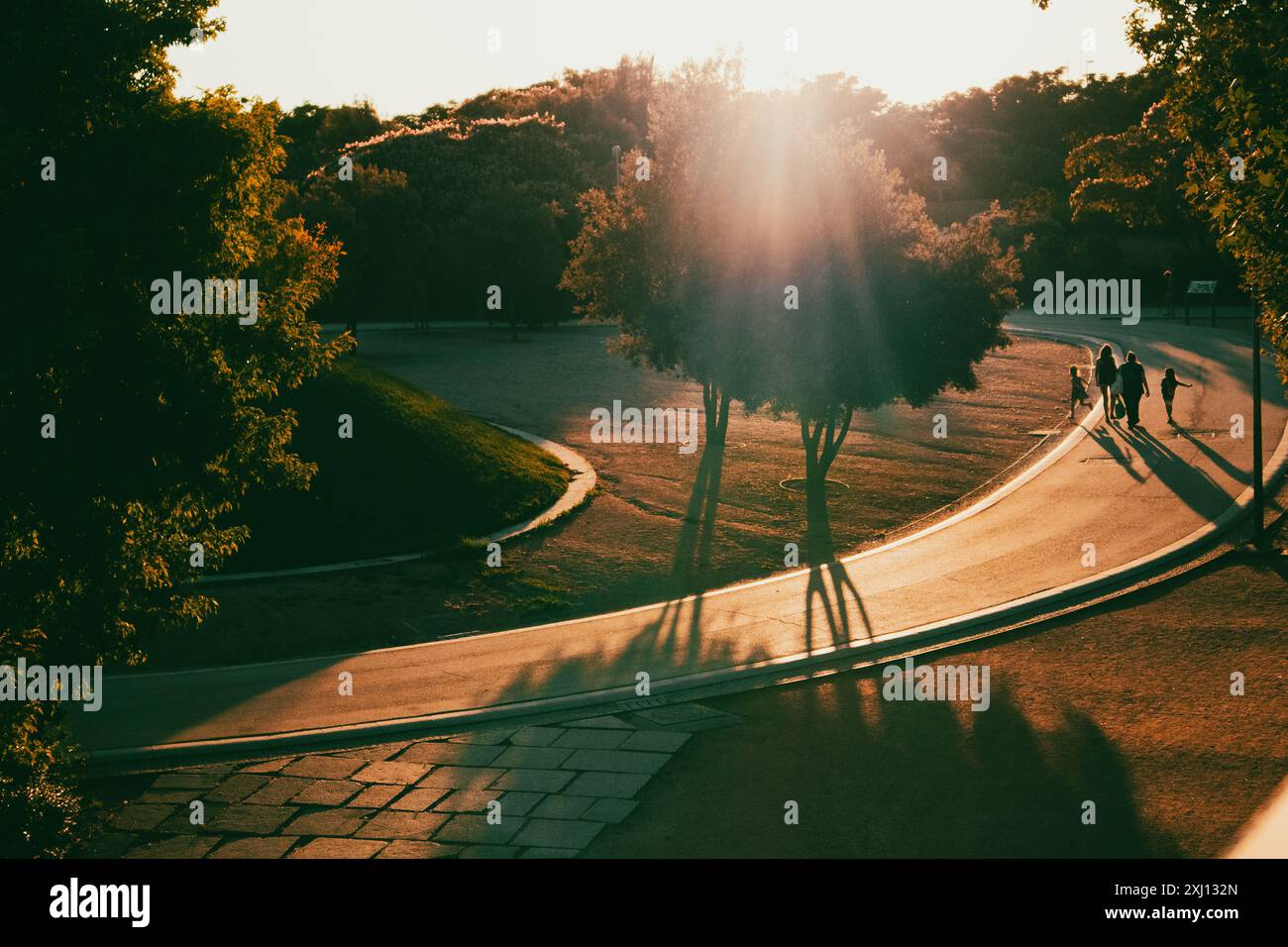 Silhouettes of people walking away down a winding path, road in a park ...