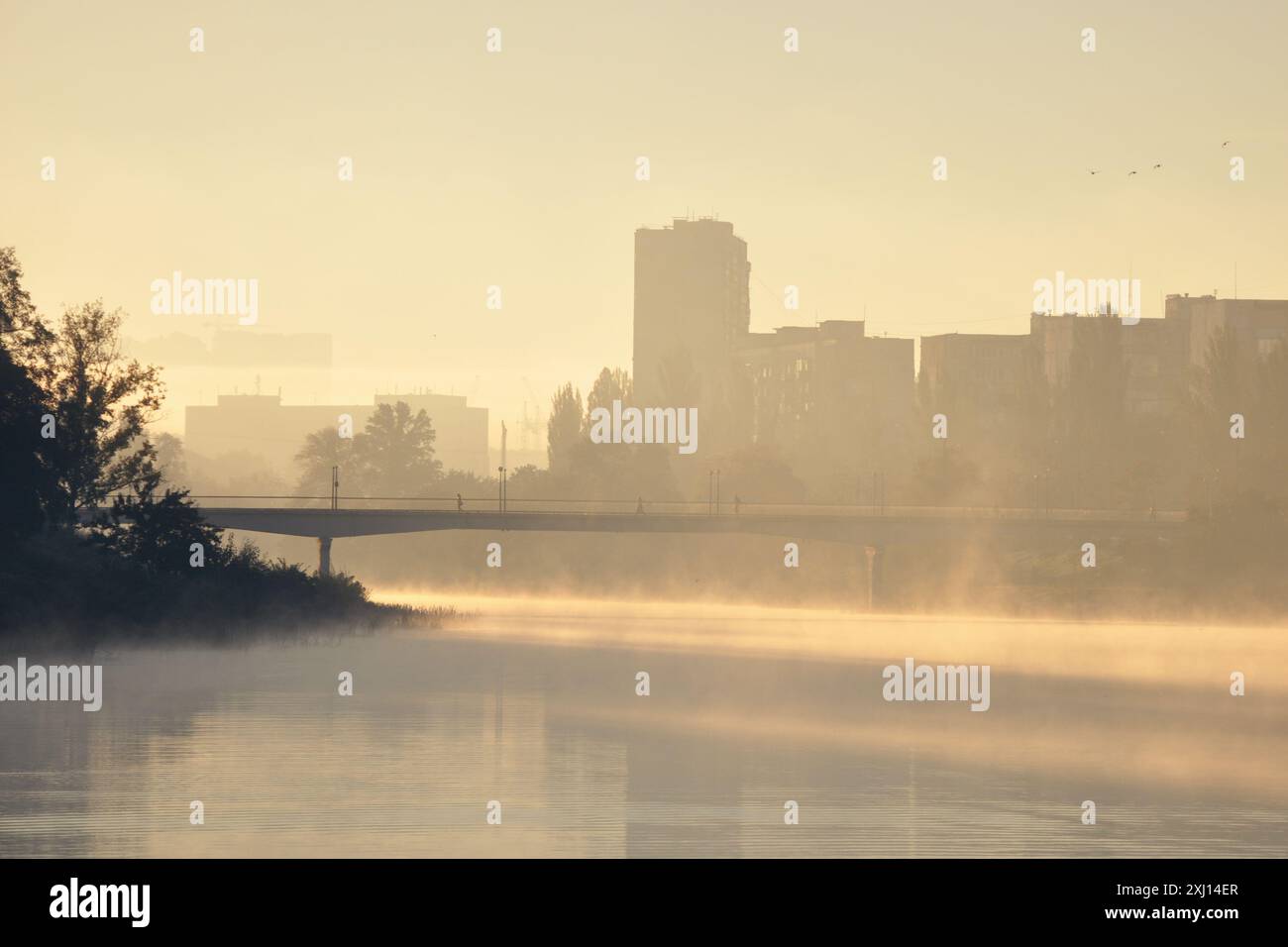 Foggy sunrise in a city. Fog on the water of river canal. Pedestrian ...
