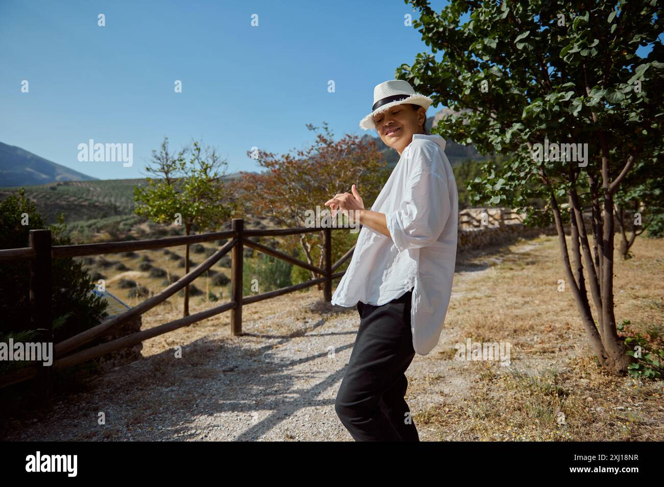 A cheerful individual wearing a hat and white shirt, enjoying a sunny ...