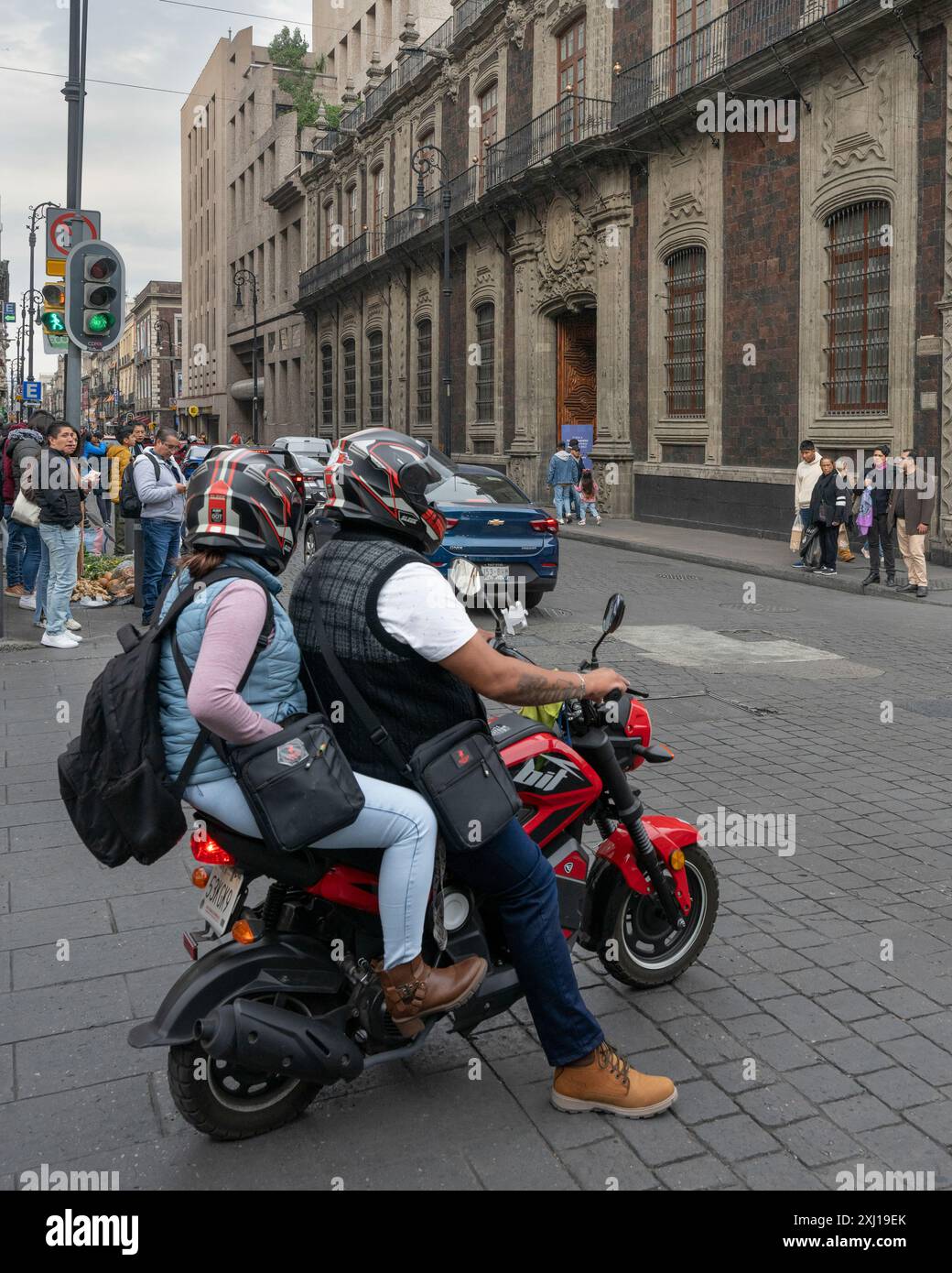 Couple riding a motorcycle and pedestrians on a street in Mexico City ...