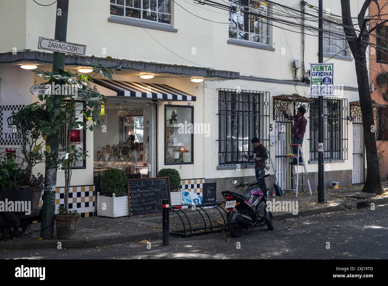 Workmen painting the bars on the exterior of a building in Coyoacan ...