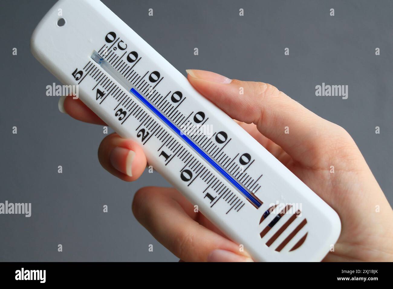 A womans hand with a plastic mercury thermometer shows high air ...