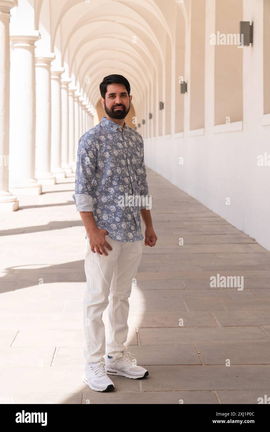 A modern, stylish Pakistani man with a dark beard and light clothes ...