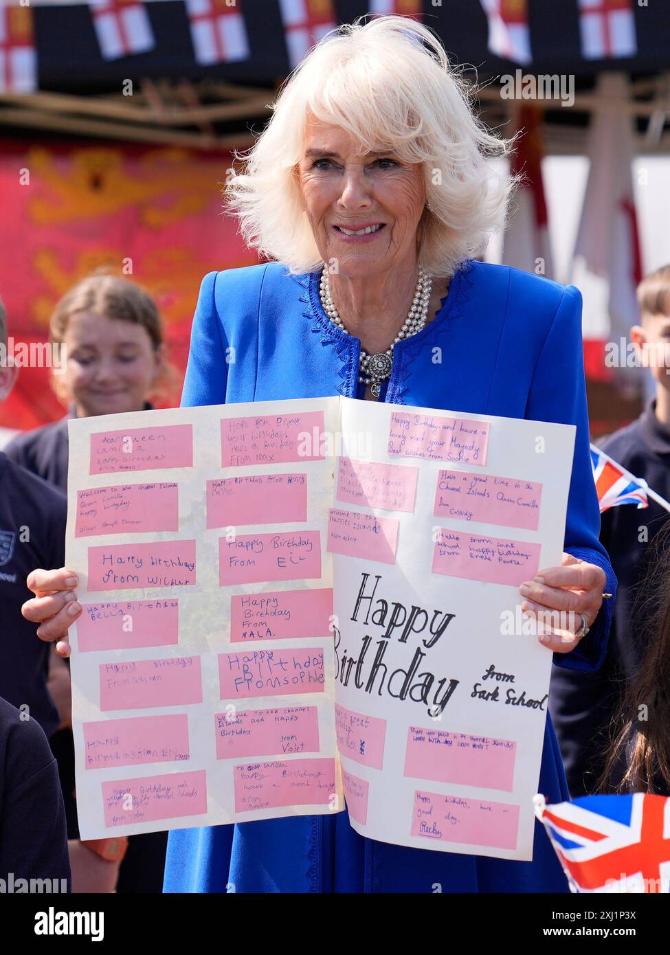 Queen Camilla poses with local school children holding a birthday card ...