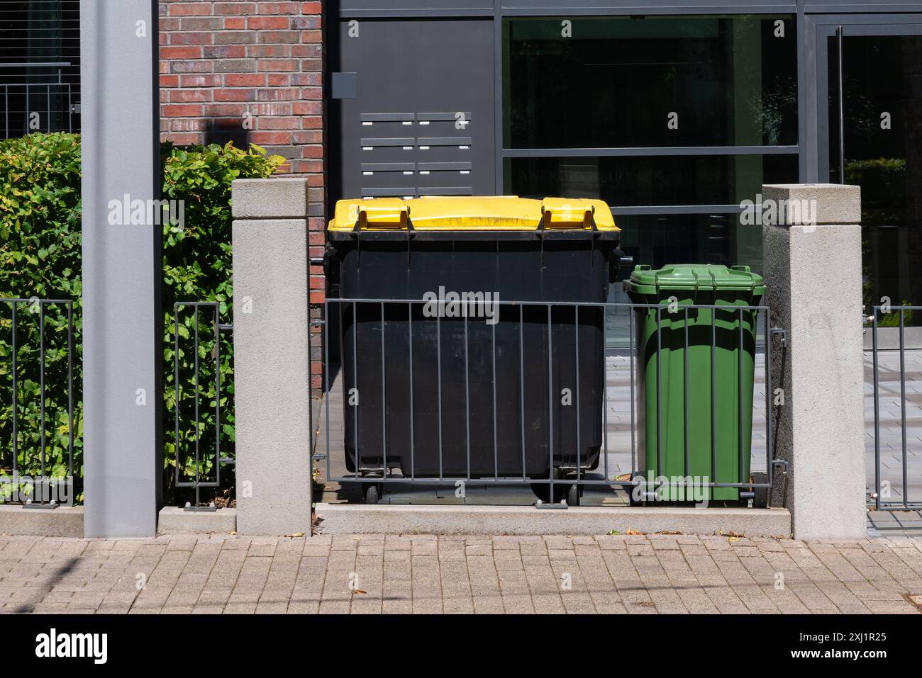 Two large bins, one yellow and black and the other green, are located ...