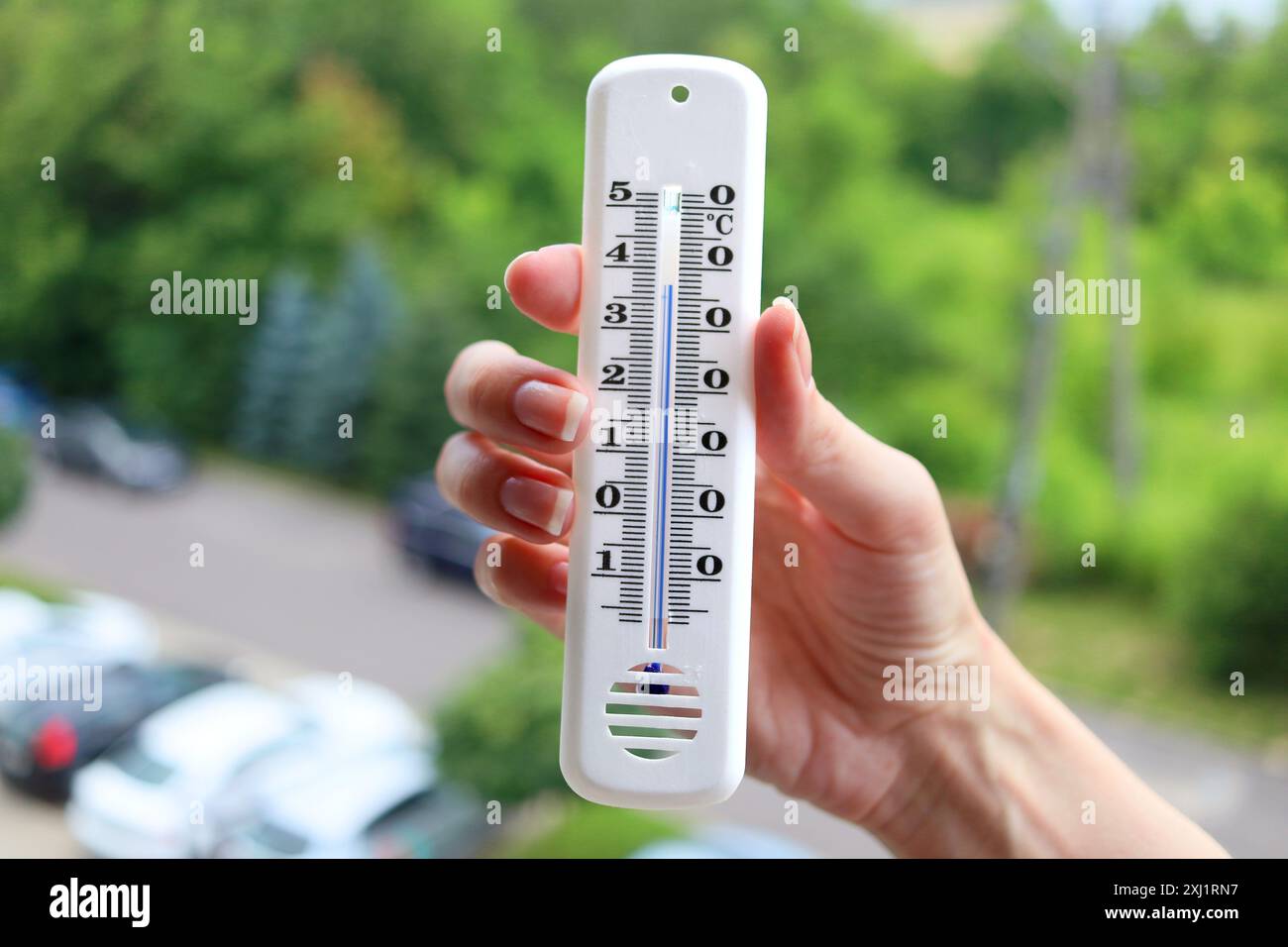 A womans hand with a plastic mercury thermometer shows high air ...