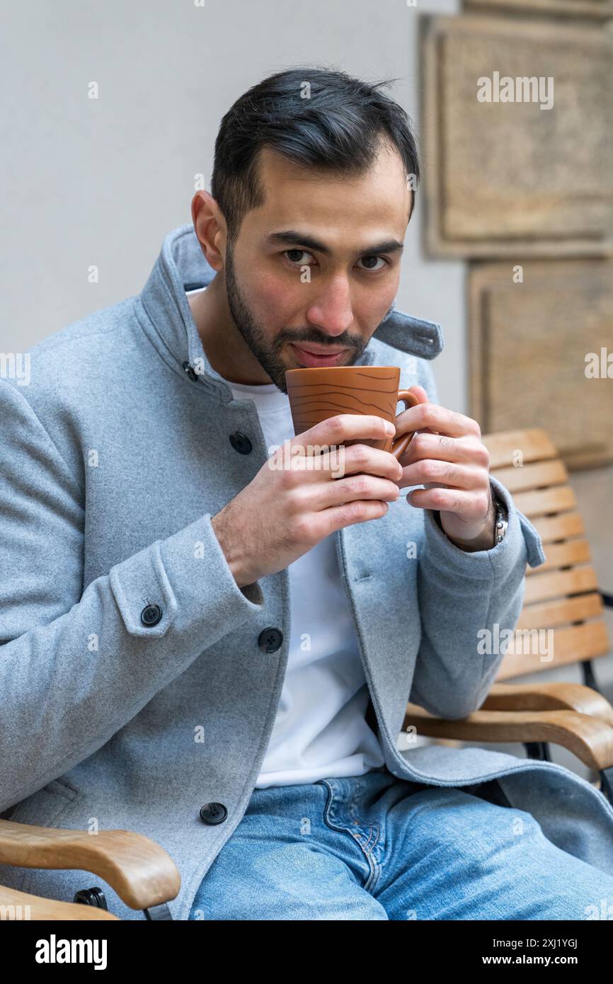 A young handsome guy of Asian appearance with a neat beard in a light ...