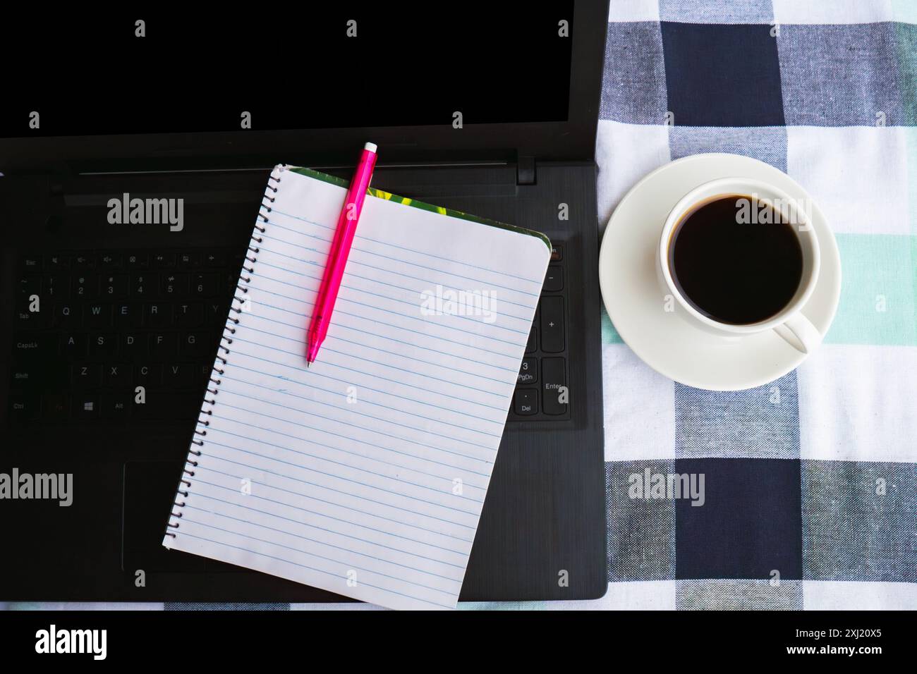 Working with a notepad, laptop, coffee in a restaurant cafe setting ...