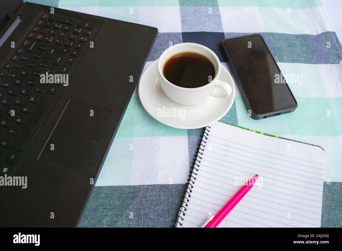 Working with a notepad, laptop, coffee in a restaurant cafe setting ...