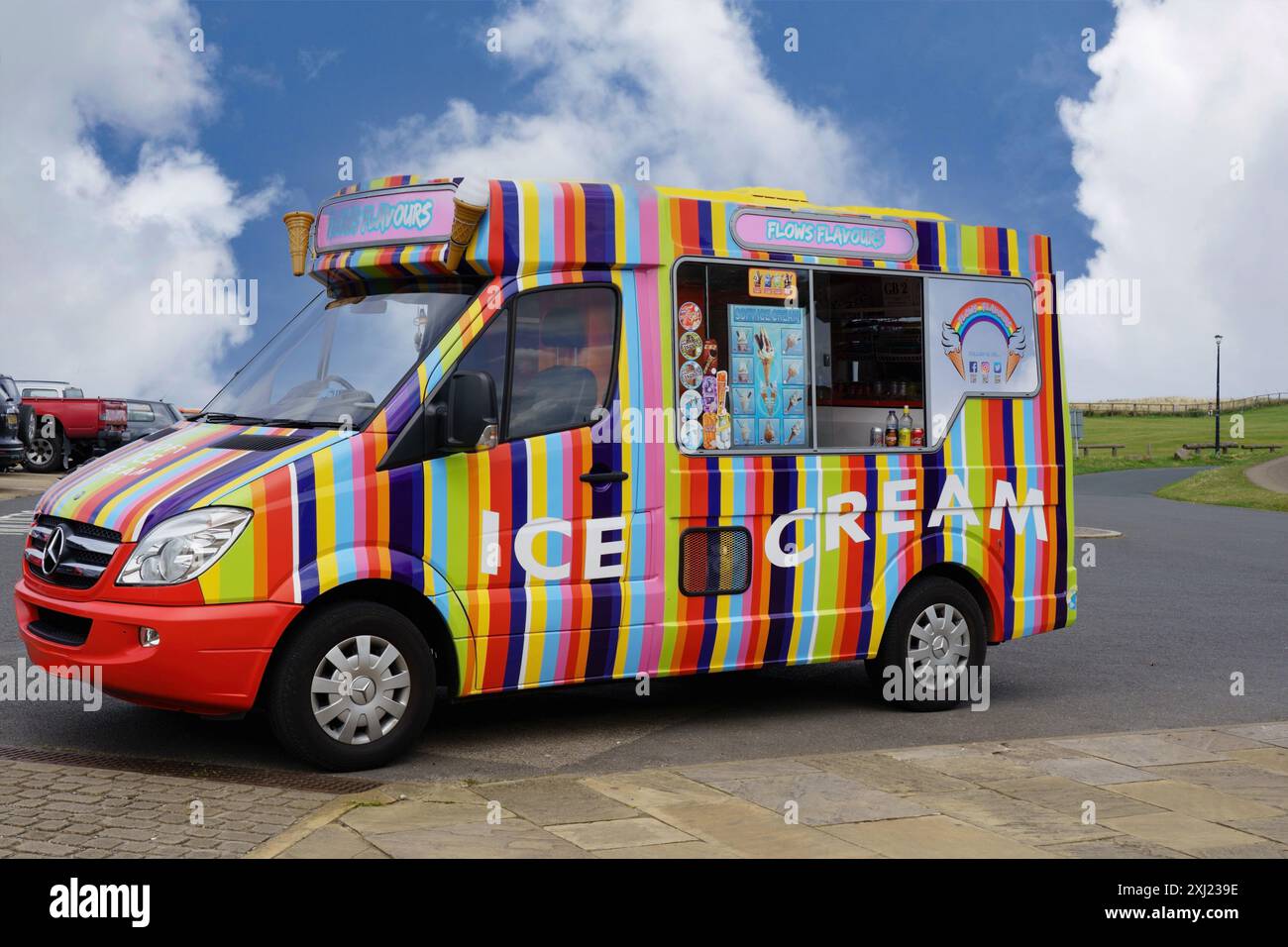 A stationary ice cream van with a rainbow of stripes and a mouth ...