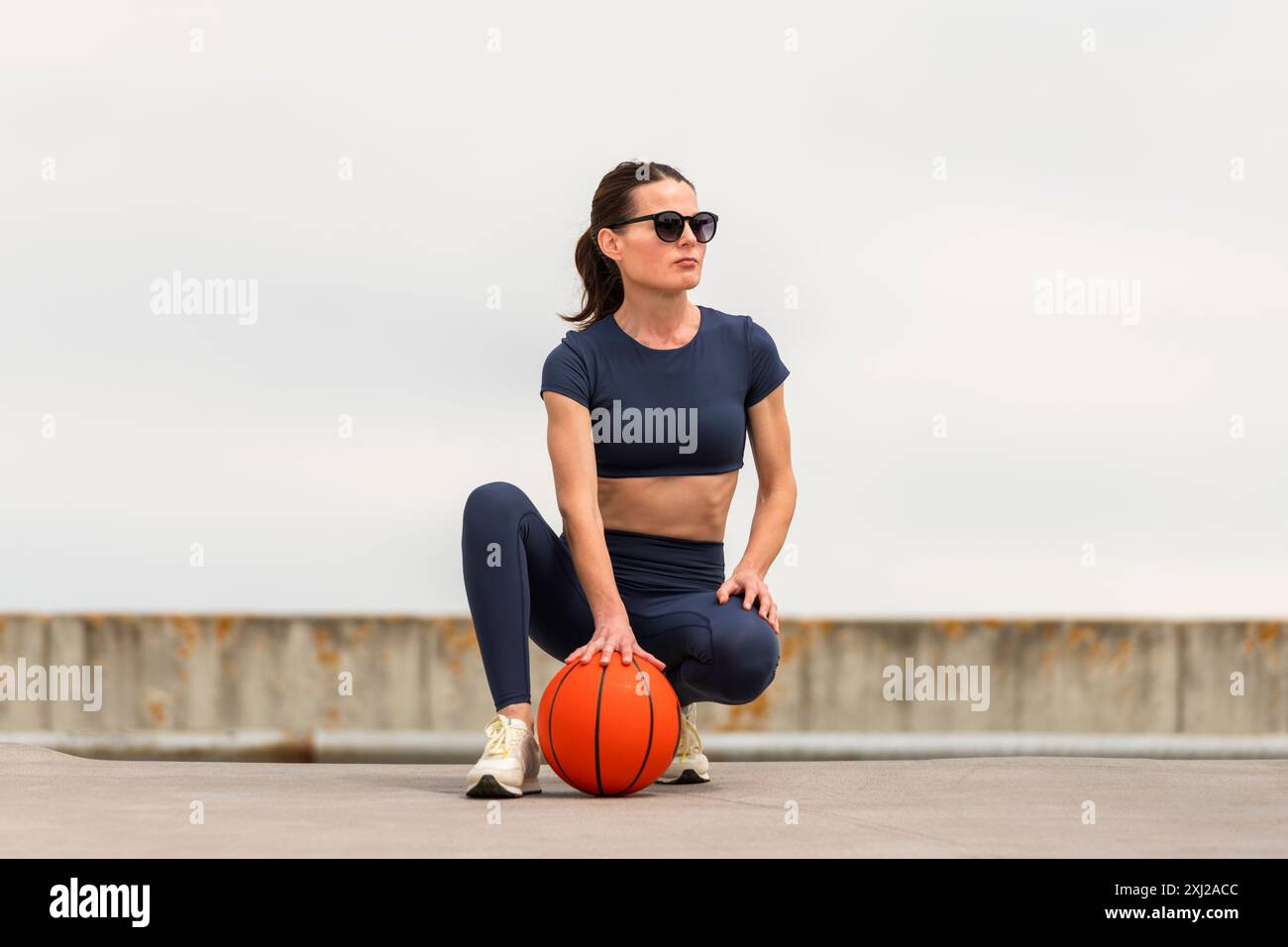 Female basketball player, crouching holding a basketball, outside in ...