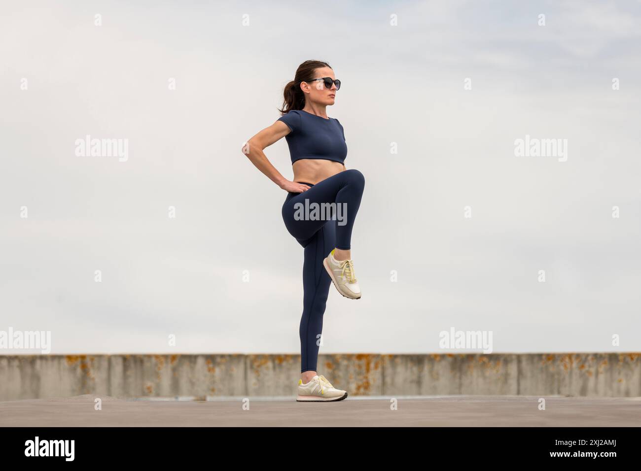 Sporty woman stretching leg muscles with standing single knee to chest ...