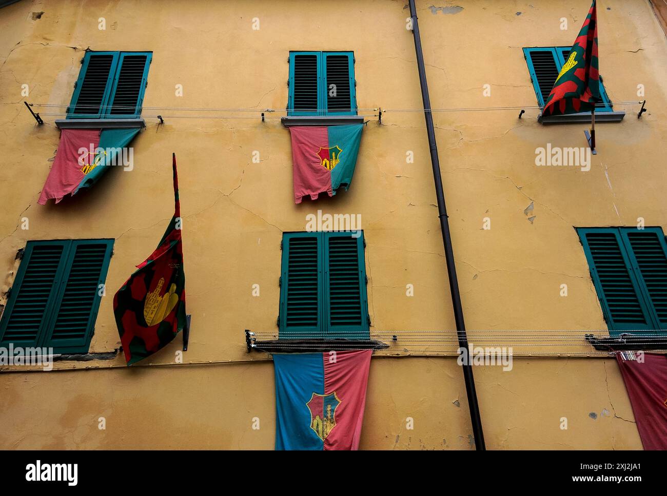 Colourful flags of the Porta Crucifera hang from a house in Arezzo ...
