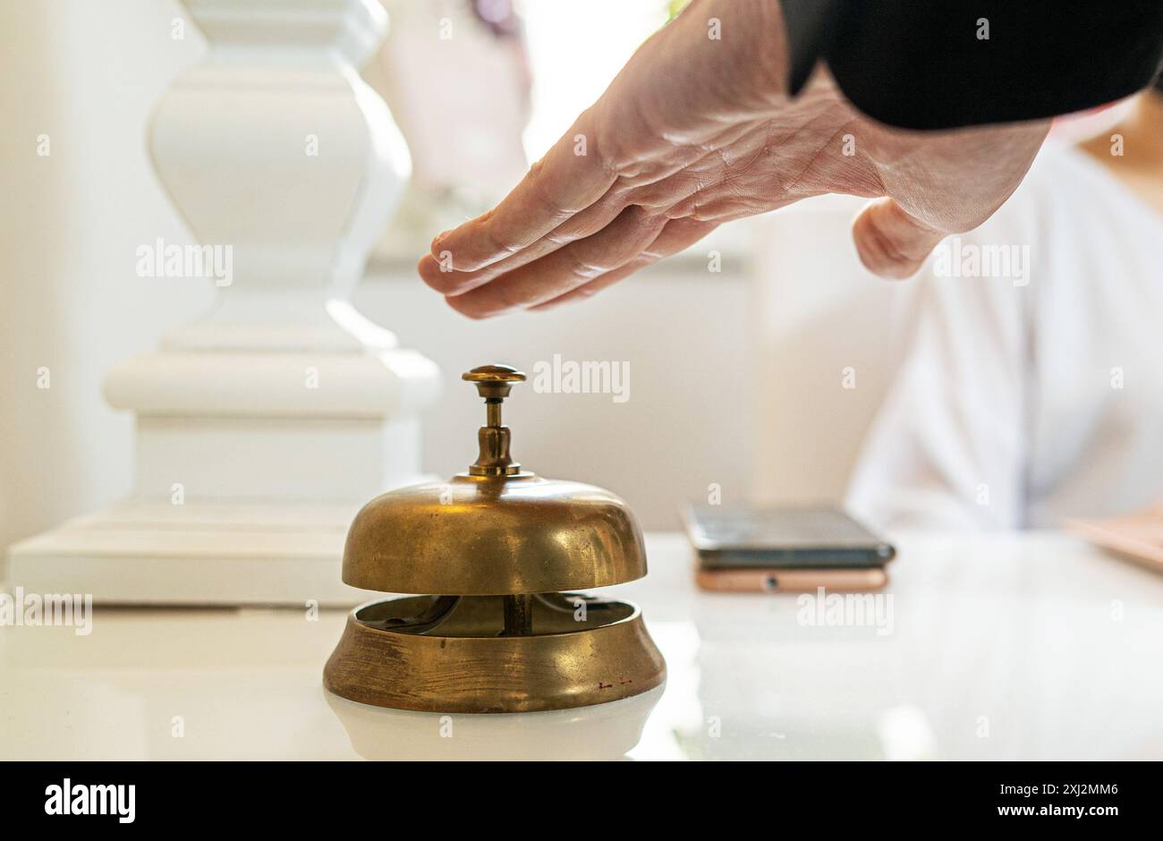 Close-up of hotel reception desk featuring antique brass service bell ...
