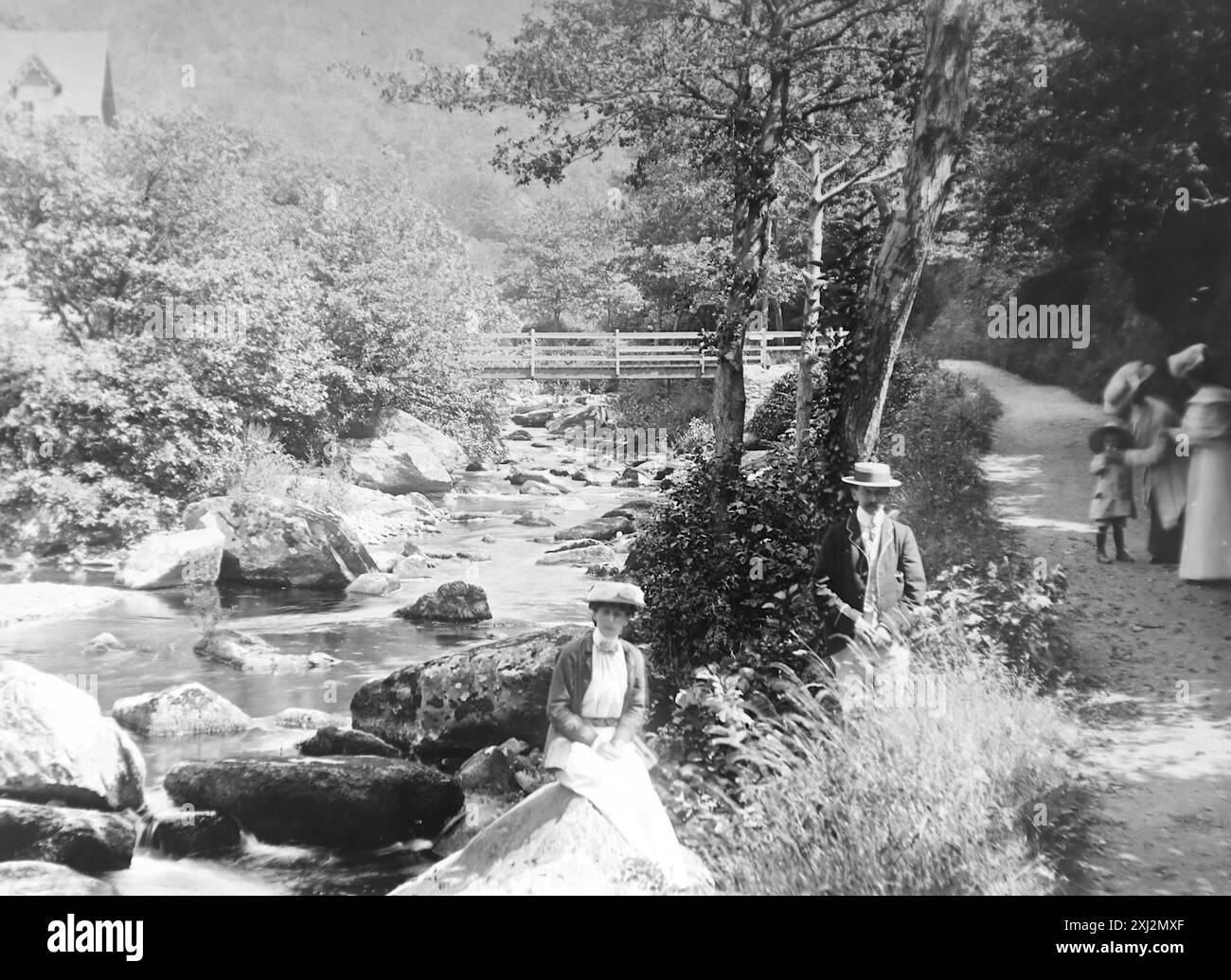 Valley of the Lyn. A number of people beside the River Lyn with a distant footbridge. Lynmouth ...