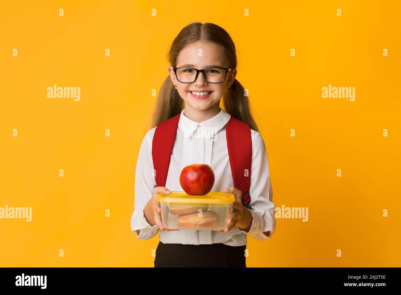 Cute Schoolgirl Holding Lunch Box Over Yellow Studio Background Stock ...