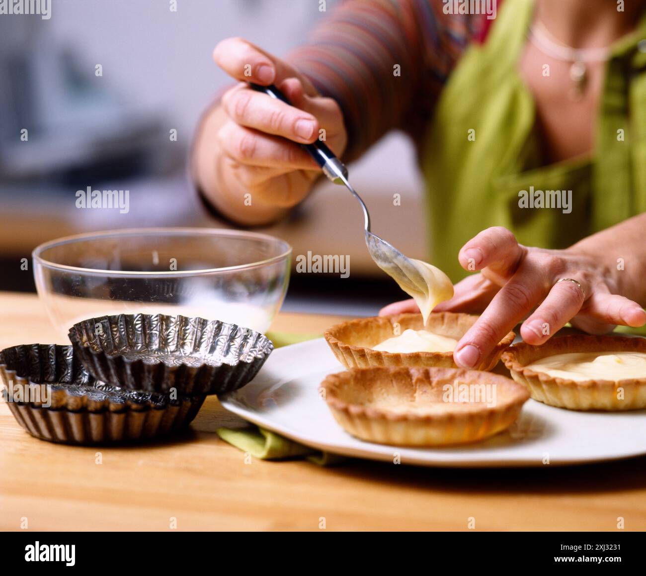 Filling the cooked pastry moulds with lemon curd Stock Photo - Alamy