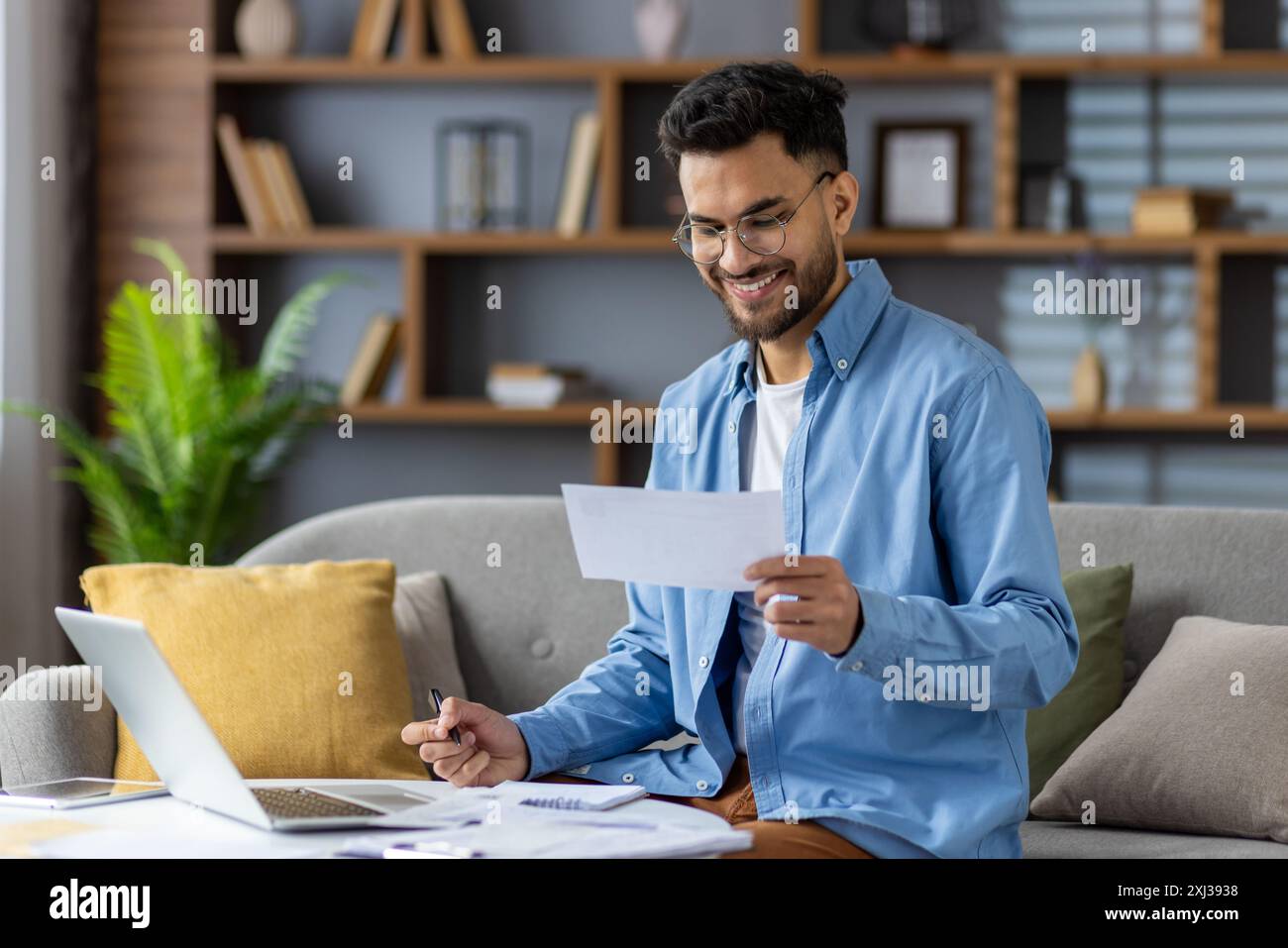 An Indian man concentrating on paperwork at a cozy home setting. He is ...
