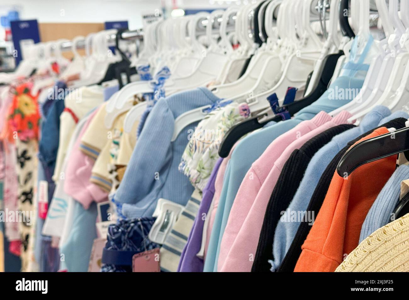 a clothing rack filled with various colorful garments on hangers in a ...