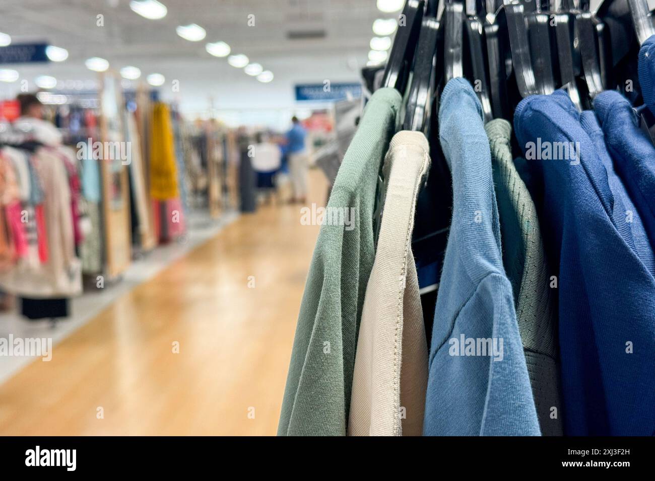 clothing rack with assorted garments in a retail store, with a blurred ...
