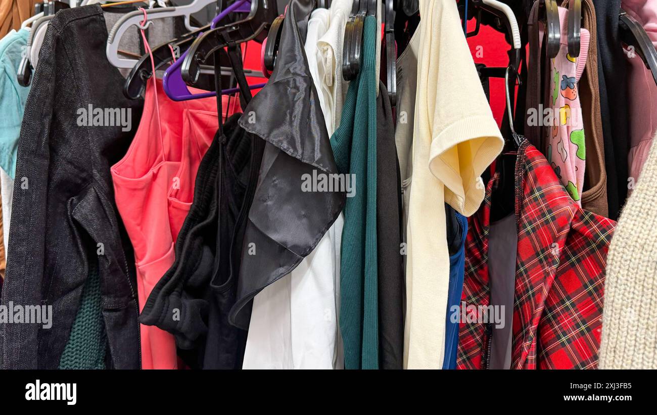 a clothing rack filled with a variety of garments, including jackets ...