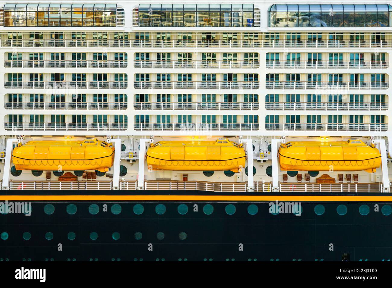 Side view of three yellow lifeboats and balconies on a large cruise ...