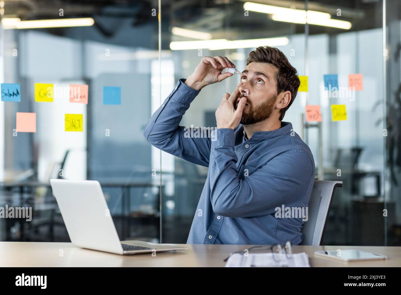 Businessman taking care of eyes with eye drops in modern office. Man ...