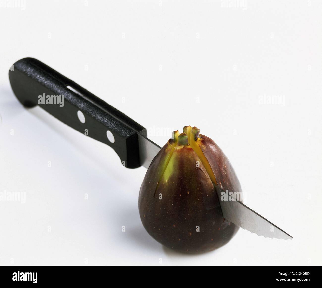 Cutting a fig in two Stock Photo - Alamy